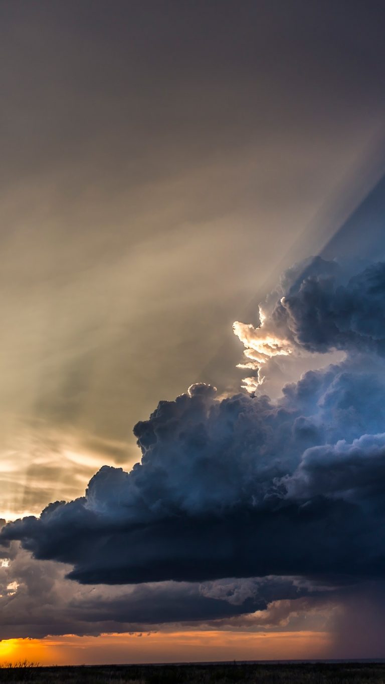 Extreme weather at sunset with rays of light over storm clouds ...