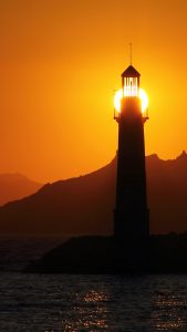 Seascape at sunset with lighthouse on the coast, seaside town of ...